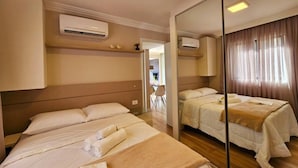 Quarto de hotel com duas camas, um espelho grande e um aparelho de ar condicionado.