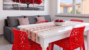 Uma sala de jantar moderna com uma mesa branca, cadeiras vermelhas e uma tigela de frutas.