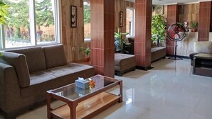 Uma sala de estar ampla com um sofá, uma mesa de centro de vidro e um ventilador.