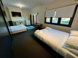 Quarto de hotel com duas camas, uma escrivaninha, uma cadeira, uma televisão e uma janela com vista para o exterior.