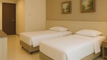 Quarto de hotel com duas camas, uma porta e duas pinturas na parede.