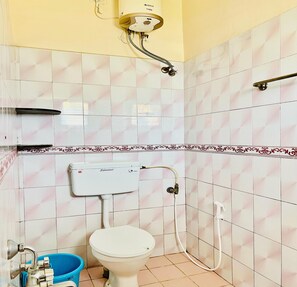 Uma casa de banho com sanita, chuveiro e lavatório.