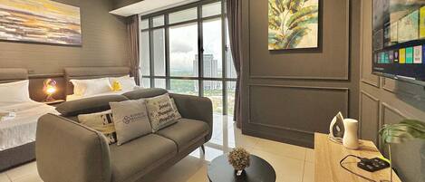 Quarto de hotel moderno com cama, sofá, televisão e vista para a cidade.