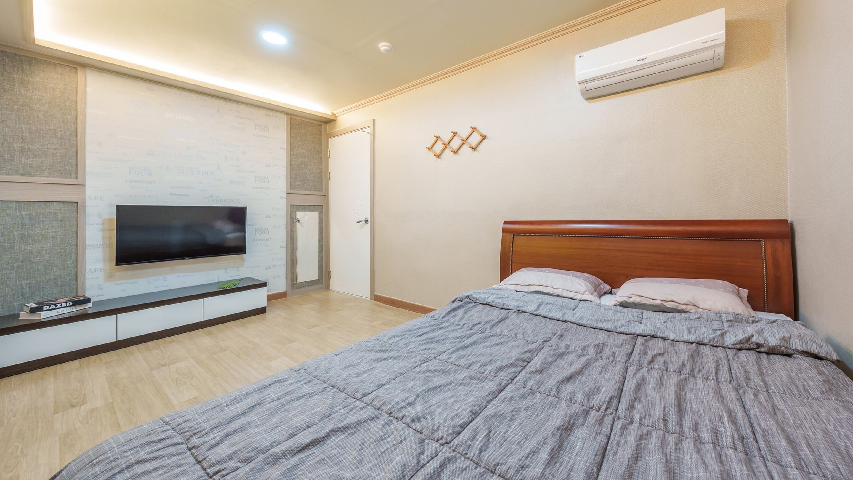 Quarto com uma cama, TV fixada na parede e aparelho de ar condicionado.