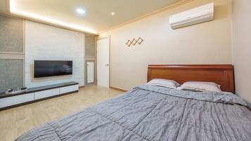 Quarto com uma cama, TV fixada na parede e aparelho de ar condicionado.
