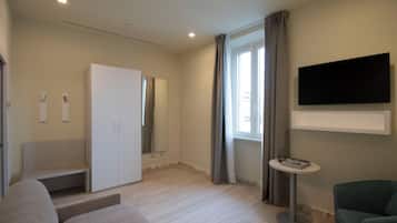 Quarto de hotel moderno com uma cama grande, um guarda-roupa, uma televisão e uma pequena mesa.