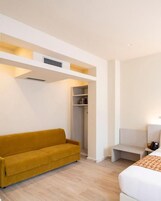 Quarto de hotel com sofá, cama, cadeira e guarda-roupa.