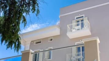 Um edifício com vários andares, escada de vidro e varandas.