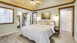 Quarto com uma cama grande, teto de madeira e ventoinha no teto.