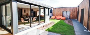 Uma casa moderna com varanda de vidro, sala de jantar e um pequeno jardim.