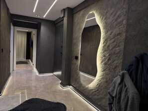 Um interior moderno com um corredor que leva a um quarto, um espelho grande e um porta-robes.