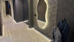 Um banheiro moderno com parede de pedra, um espelho grande e um porta-toalhas.