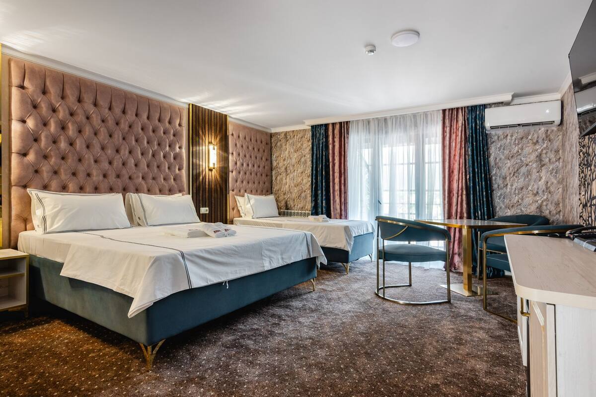 Quarto de hotel com duas camas, uma mesa e uma cadeira.
