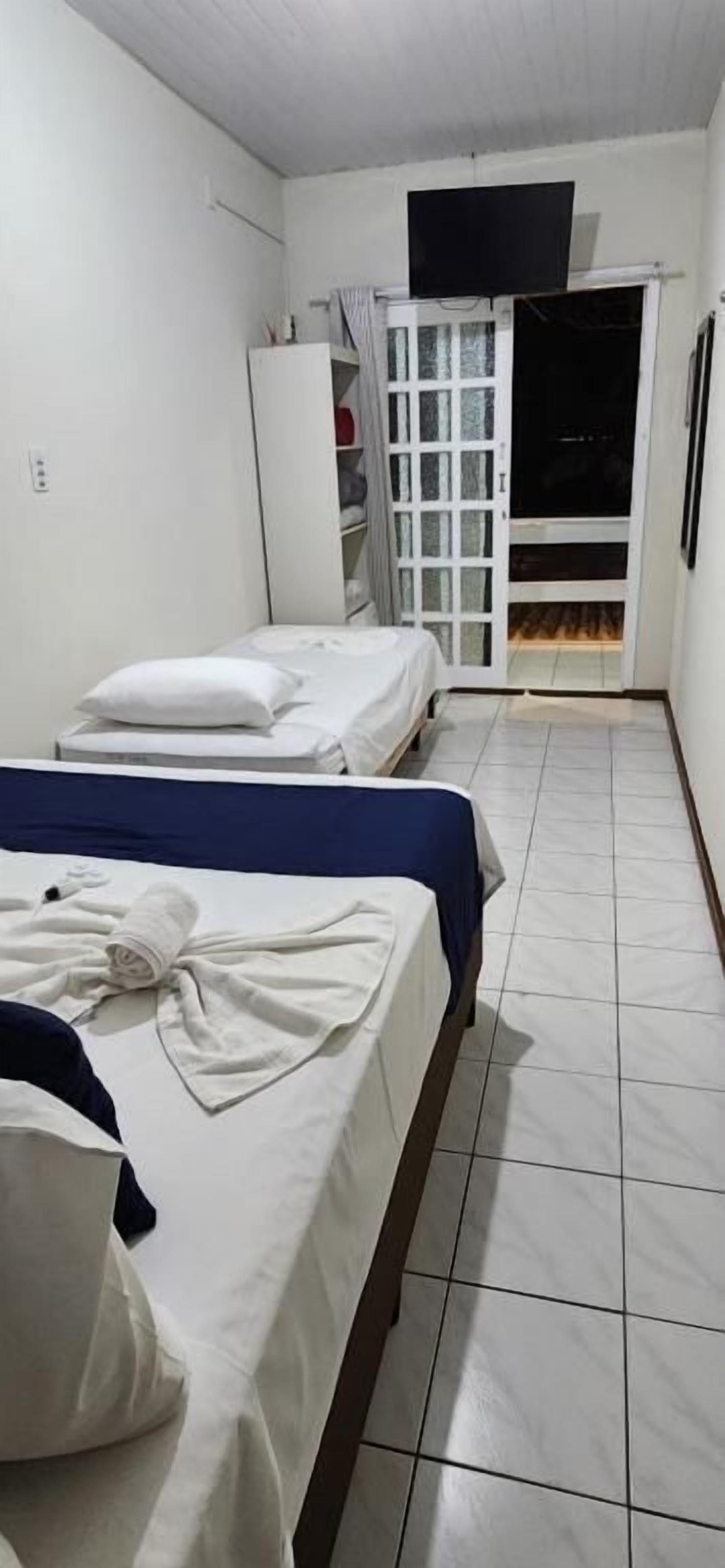 Quarto de hotel com duas camas, um guarda-roupa e porta para uma varanda.