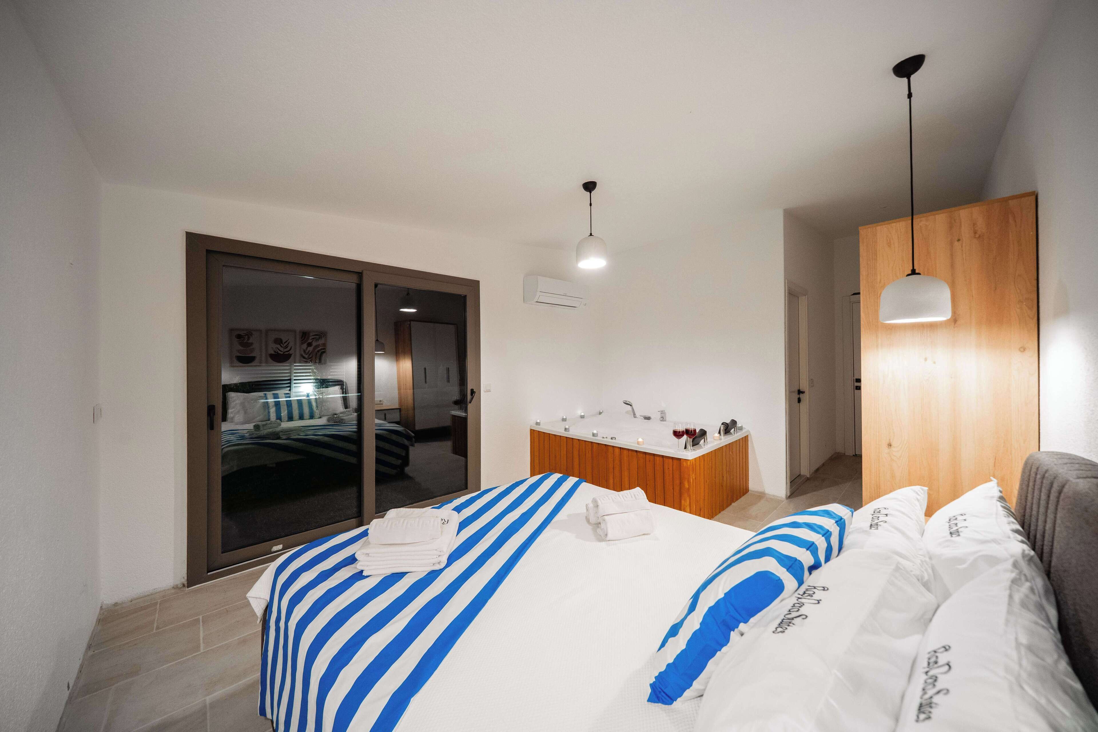 Quarto de hotel com uma cama grande, um armário de madeira com pia e uma porta de vidro deslizante para uma varanda.