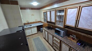 Uma cozinha compacta com geladeira, micro-ondas, pia e armários.