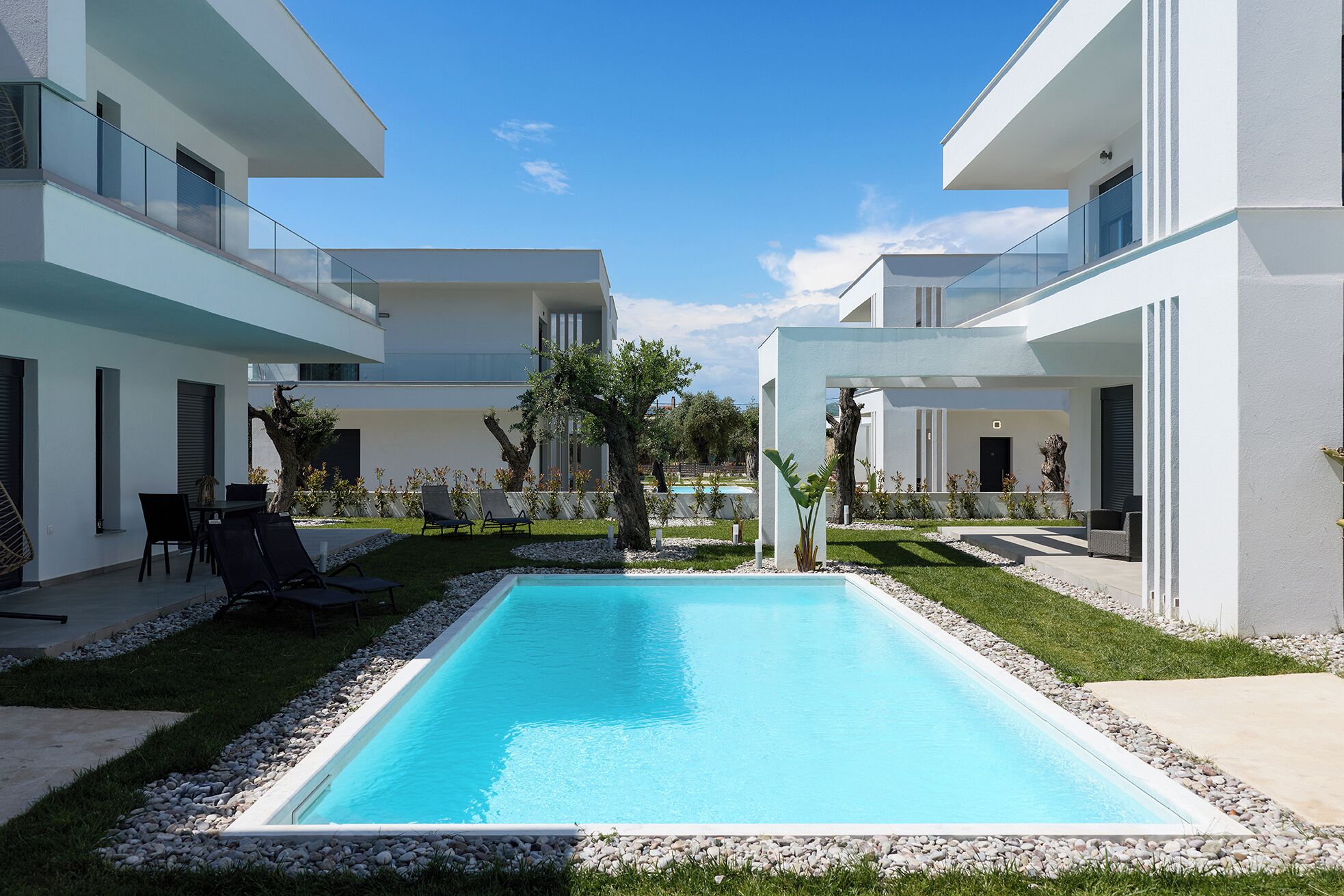 Um edifício moderno com piscina, área de estar ao ar livre e um jardim bem cuidado.