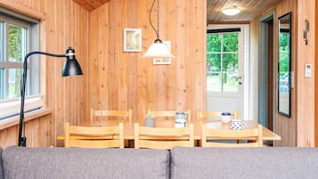 Interior em madeira com mesa, cadeiras, luminária e sofá.