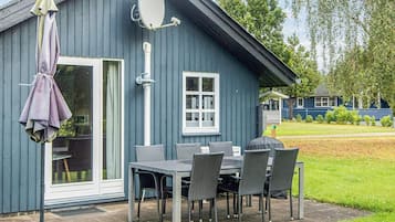 Um edifício azul com uma mesa e cadeiras no pátio, porta de correr de vidro e antena parabólica.