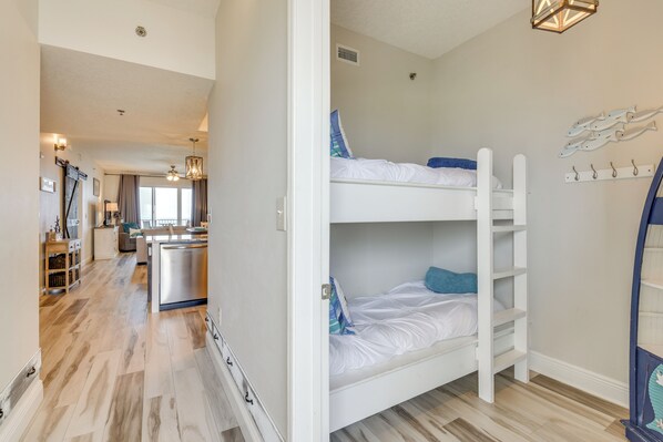 Quarto com beliche e cozinha visível através de uma porta aberta.