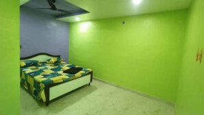 Quarto com cama, ventilador de teto e paredes verdes.