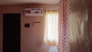 Um corredor com uma porta fechada, um ar condicionado fixado na parede e uma cortina estampada.