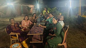 Um grupo de pessoas sentadas ao redor de uma mesa ao ar livre à noite.