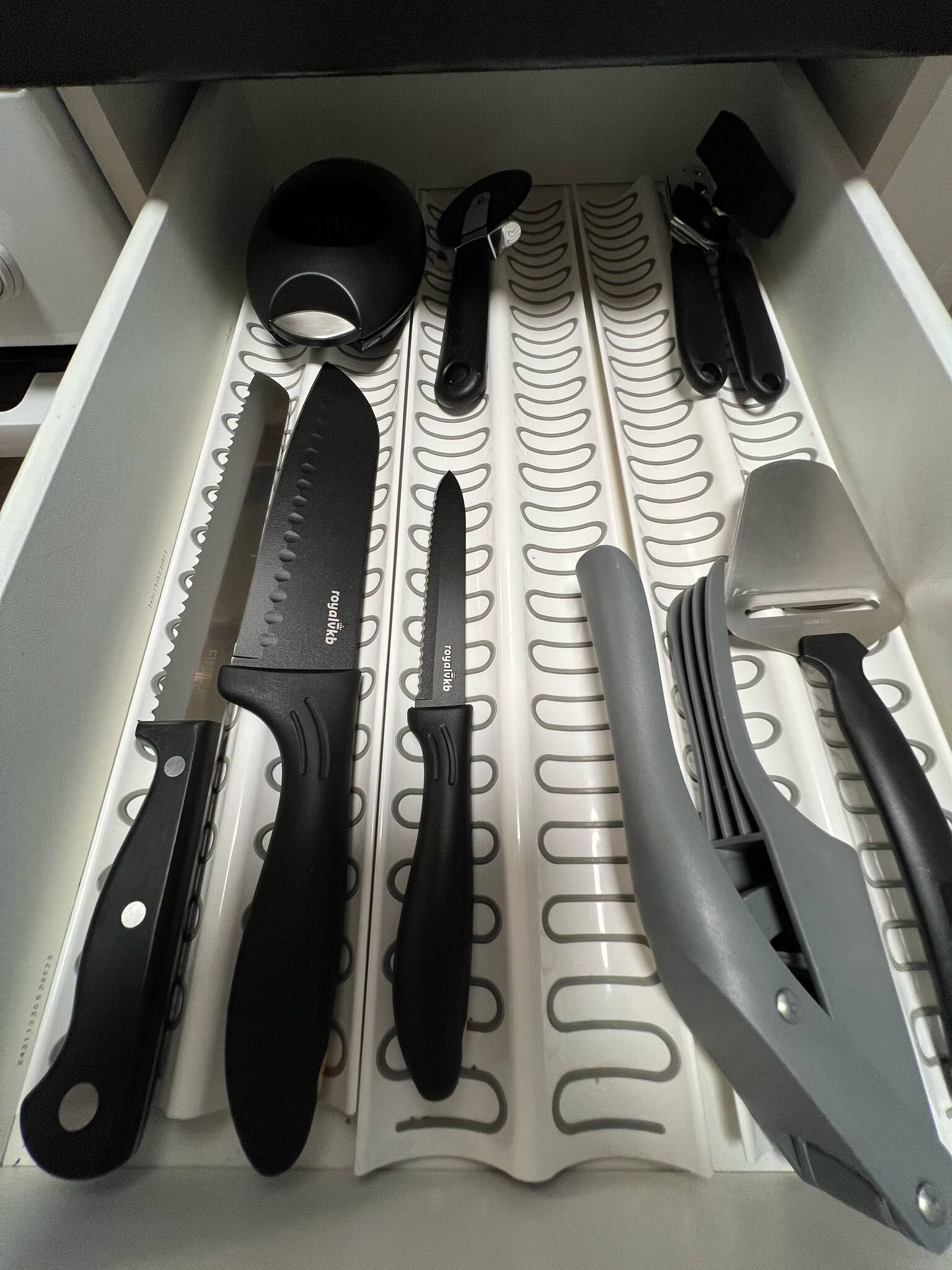 Uma gaveta com diversos facas e utensílios de cozinha organizados em um suporte.