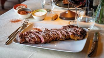 Bife em um prato branco, com faca e garfo ao lado.