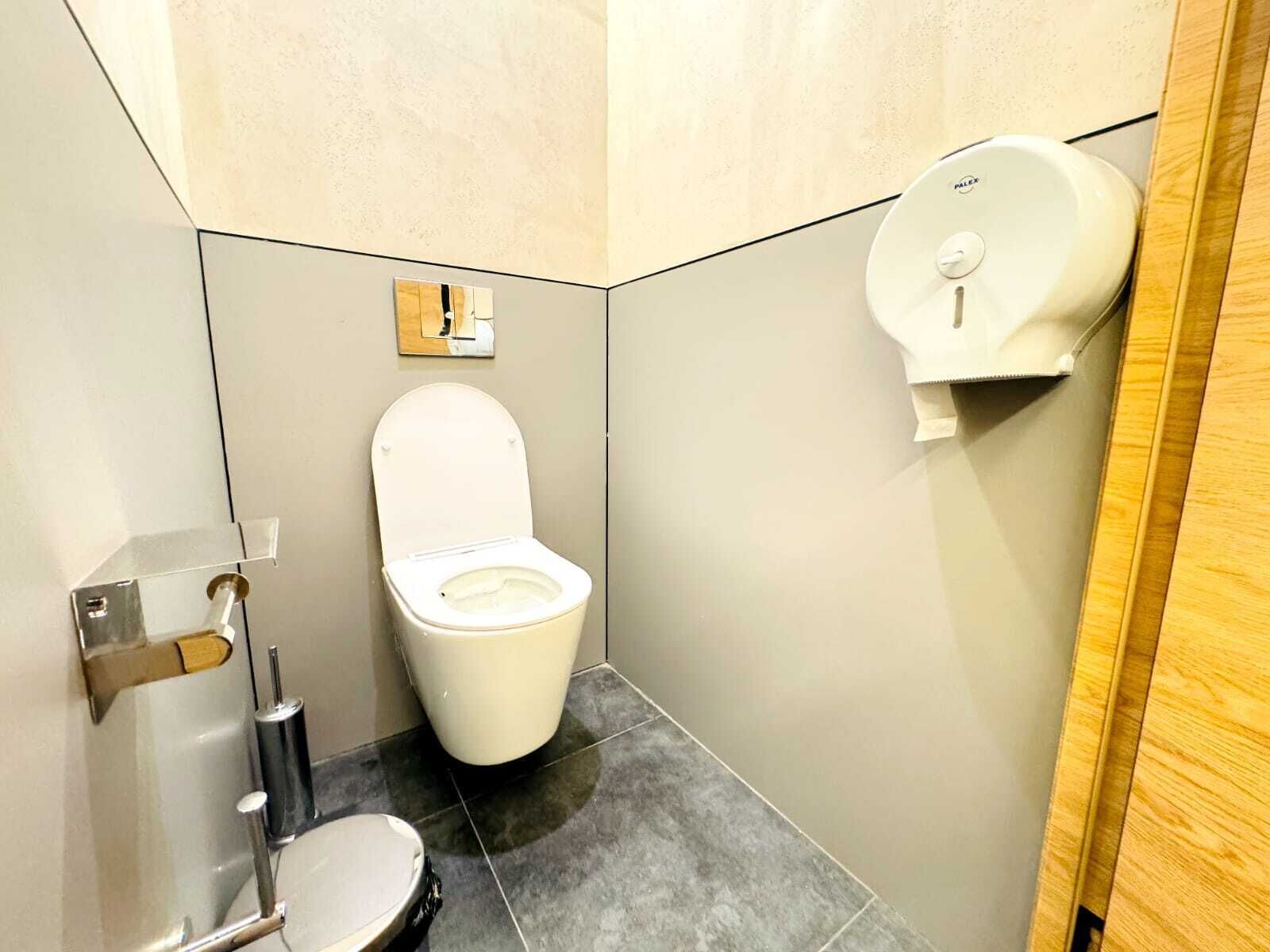 Casa de banho pequena e moderna com sanita, bidé e dispensador de toalhas de papel.