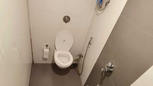 Casa de banho pequena e estreita, com sanita, bidé e secador de mãos.