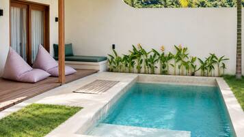 Piscina com deck de madeira e área de estar verde.