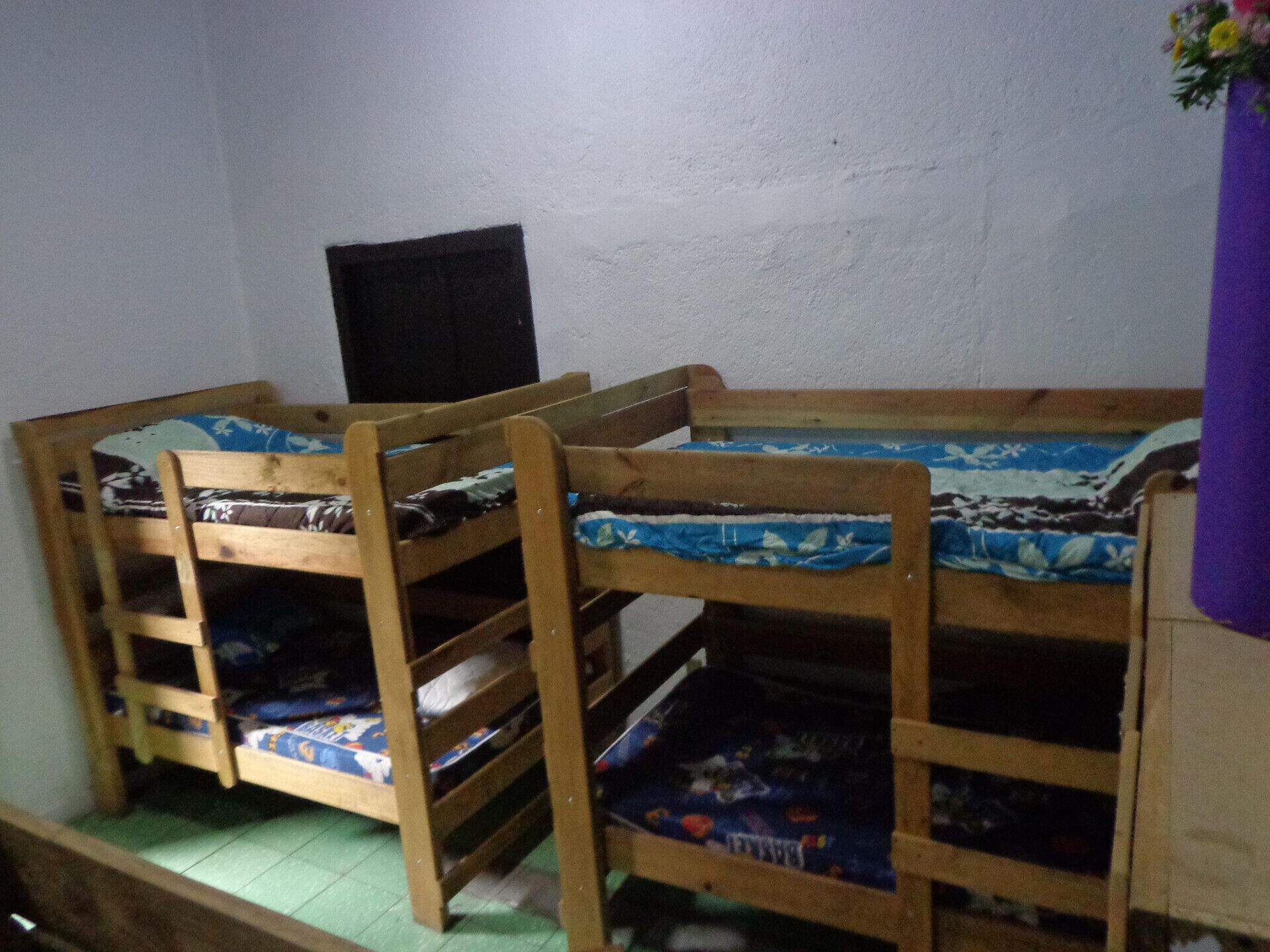 Duas beliches com estrutura de madeira e roupa de cama azul.