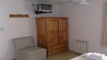 Um quarto com um guarda-roupa de madeira, uma cama pequena, uma cadeira e um radiador.