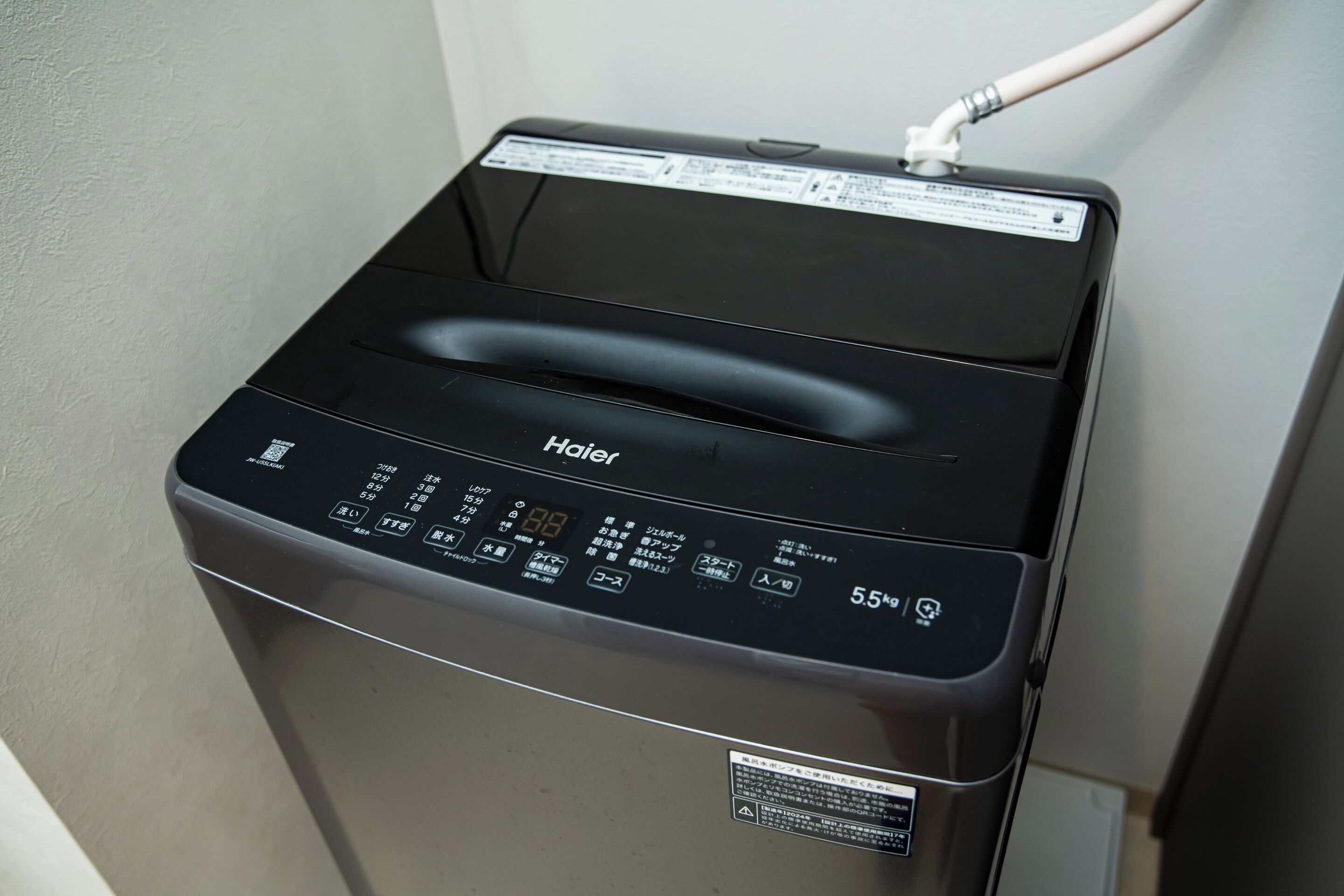 Máquina de lavar compacta, preta, de abertura frontal, com visor digital e painel de comandos, e capacidade de 5,5 kg.