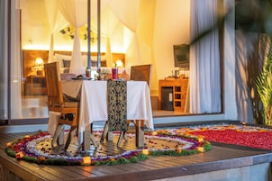 Uma área de refeições com uma mesa posta para dois, rodeada por um arranjo floral decorativo.