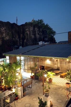 Terraço no telhado com painéis solares, plantas em vasos e área de estar ao ar livre.