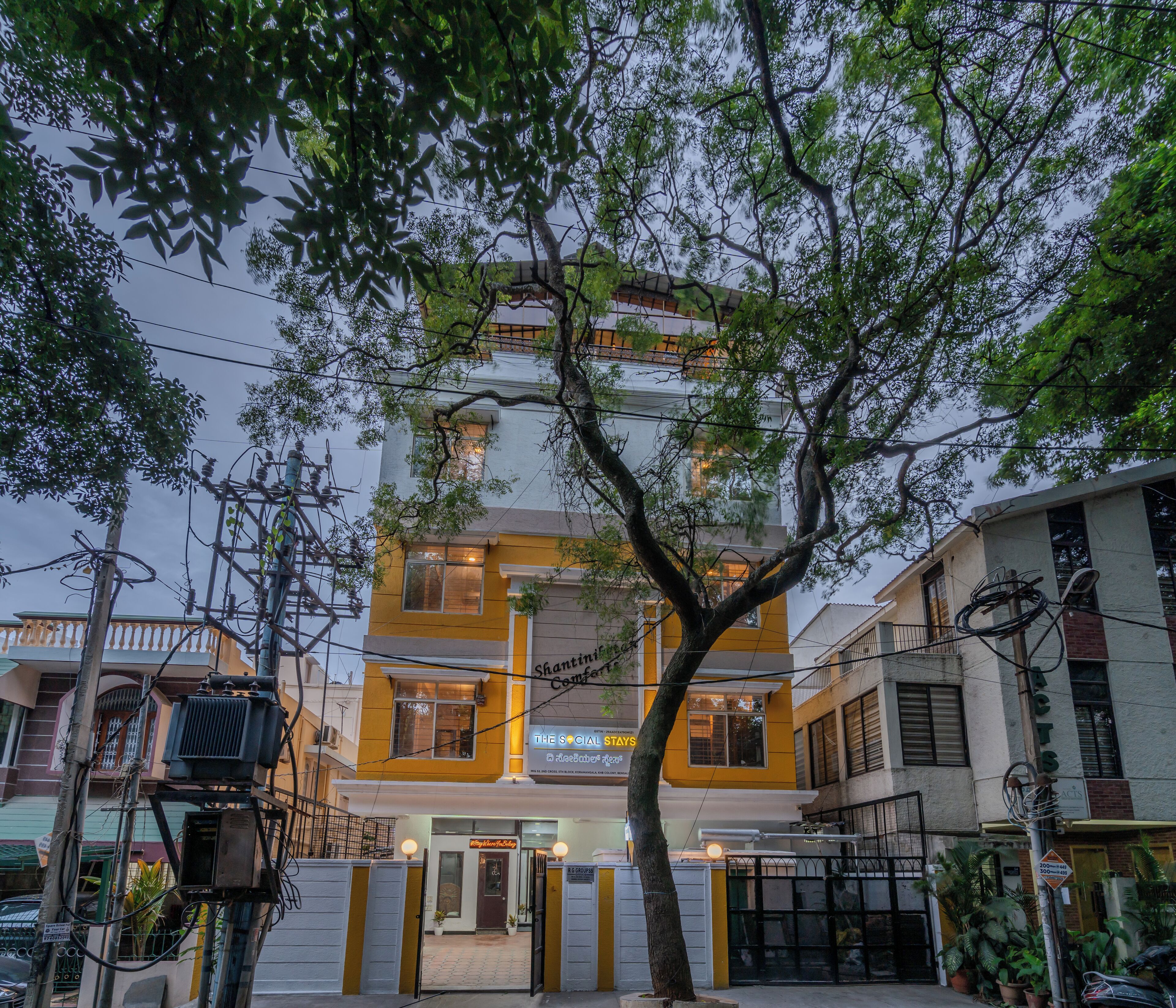 Um hotel com fachada amarela, várias varandas e uma placa indicando 'The Social Stays'.