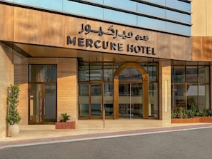 Exterior do Hotel Mercure com fachada moderna, grandes janelas de vidro e entrada imponente.