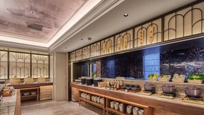Uma cozinha moderna com bancada de mármore, prateleiras de madeira e teto decorativo.