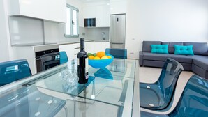 Uma cozinha moderna com armários brancos, uma geladeira de aço inoxidável e uma mesa de jantar azul com cadeiras.