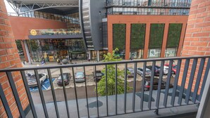 Uma varanda com vista para um estacionamento e um edifício com jardins verticais verdes.