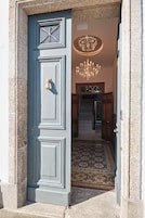 Uma entrada imponente com uma porta azul, uma luminária decorativa no teto e piso estampado.