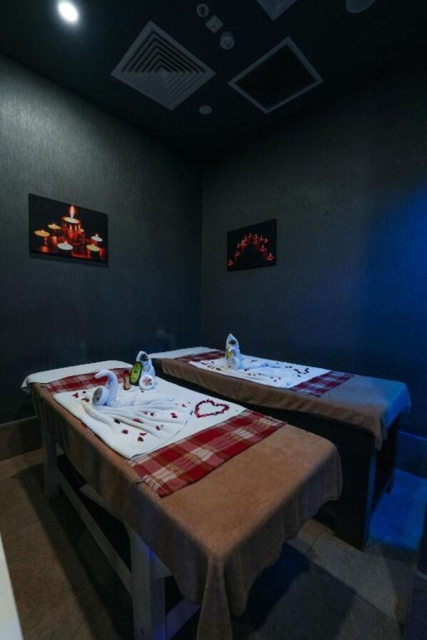 Um quarto com duas mesas de massagem, cada uma com uma toalha e um frasco de loção.