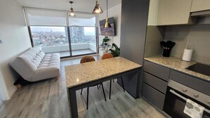 Cozinha moderna com bancada de granito, forno embutido e uma grande janela com vista para a cidade.