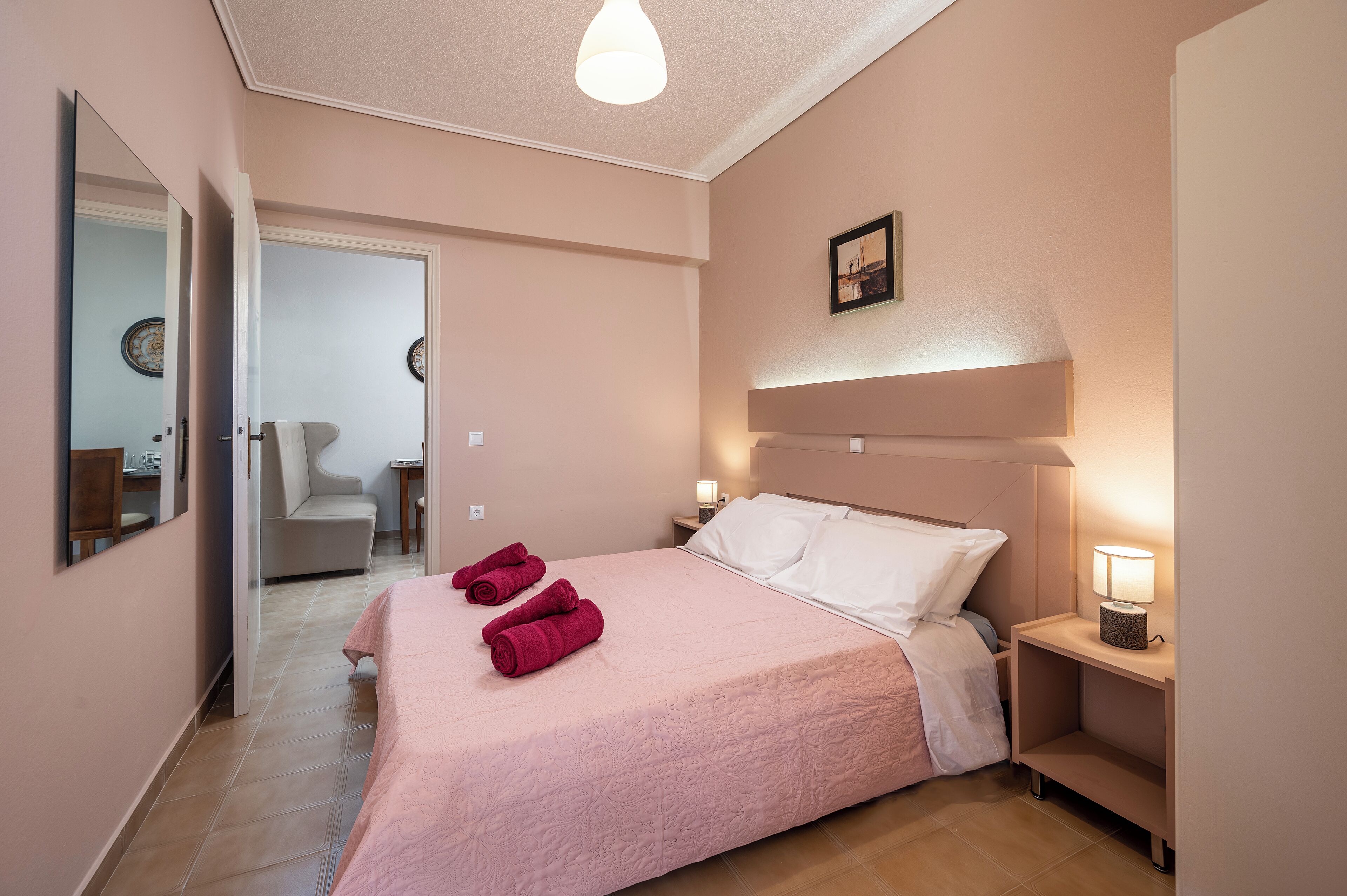 Quarto bem arrumado com cama, abajures e espelho.