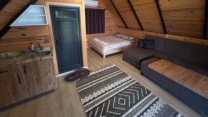 Quarto de sótão acolhedor, com cama, sofá, banheiro pequeno e janela.
