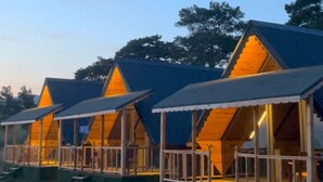 Uma fileira de cabanas de madeira com telhados inclinados e uma mesa de piquenique ao primeiro plano.