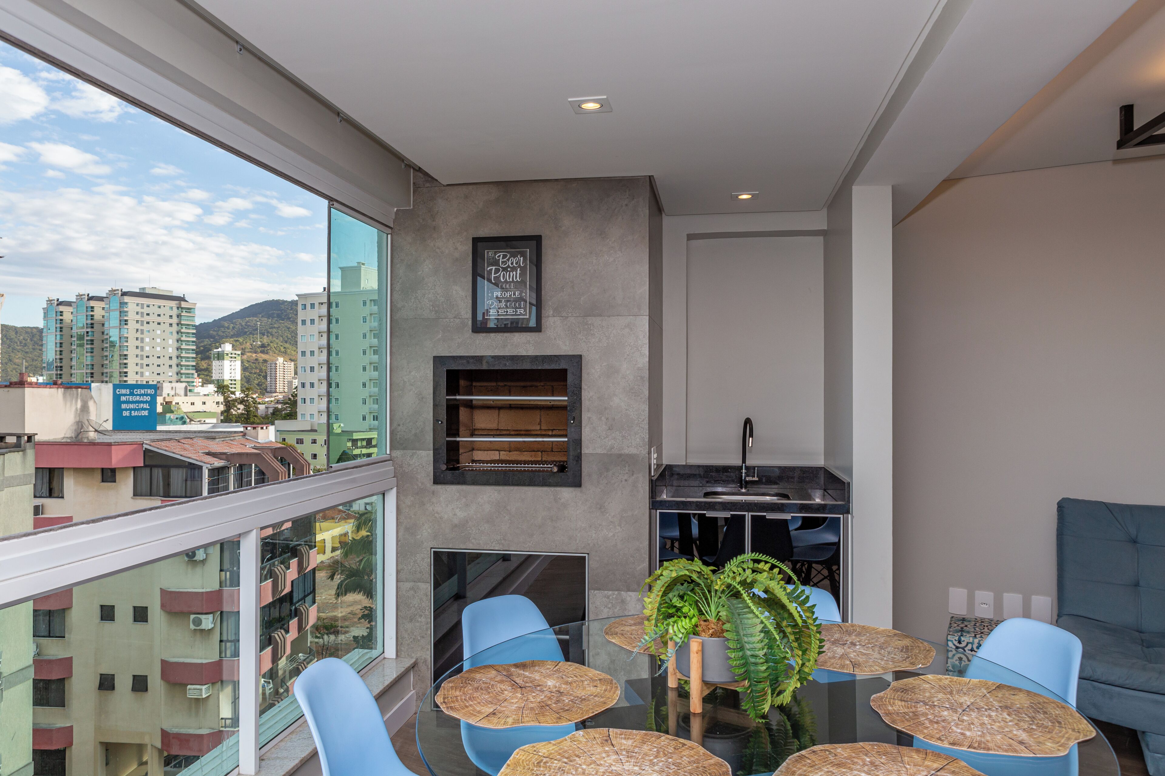 Uma sala de estar moderna com mesa de vidro, cadeiras azuis, lareira e vista para a cidade.