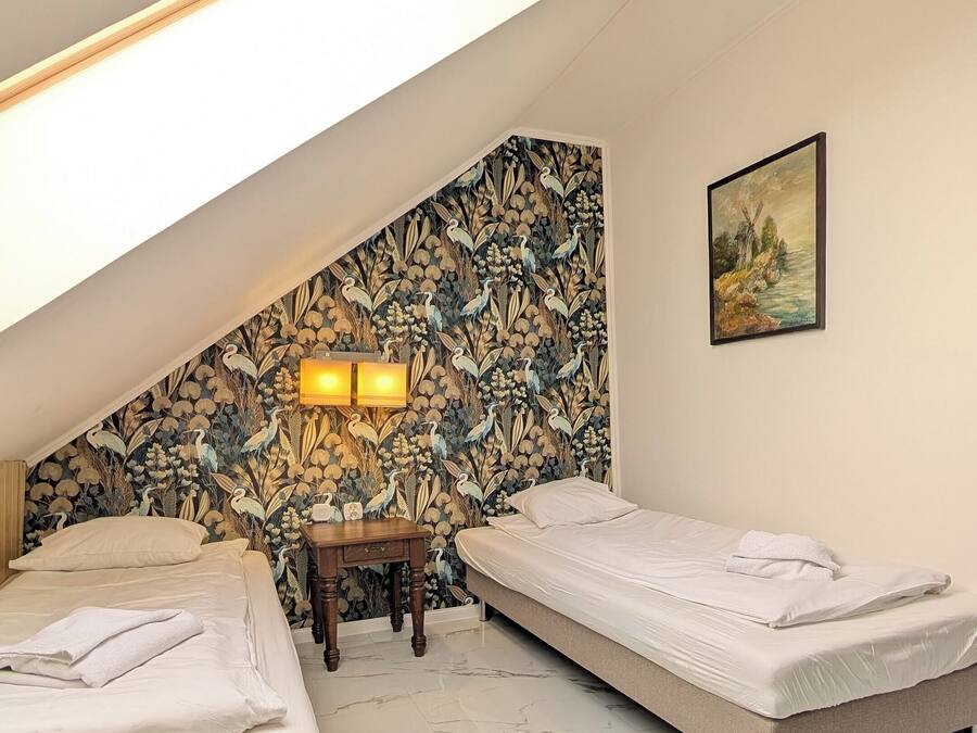 Quarto com duas camas, mesa de cabeceira, luminária e um quadro na parede.